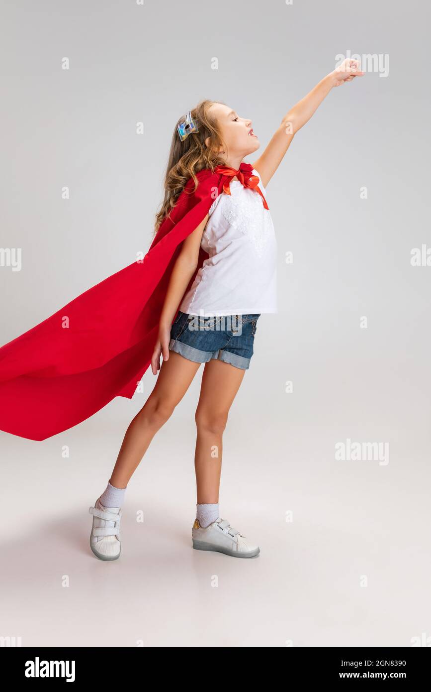 Beautiful caucasian little girl's portrait standing wearing red cape ...