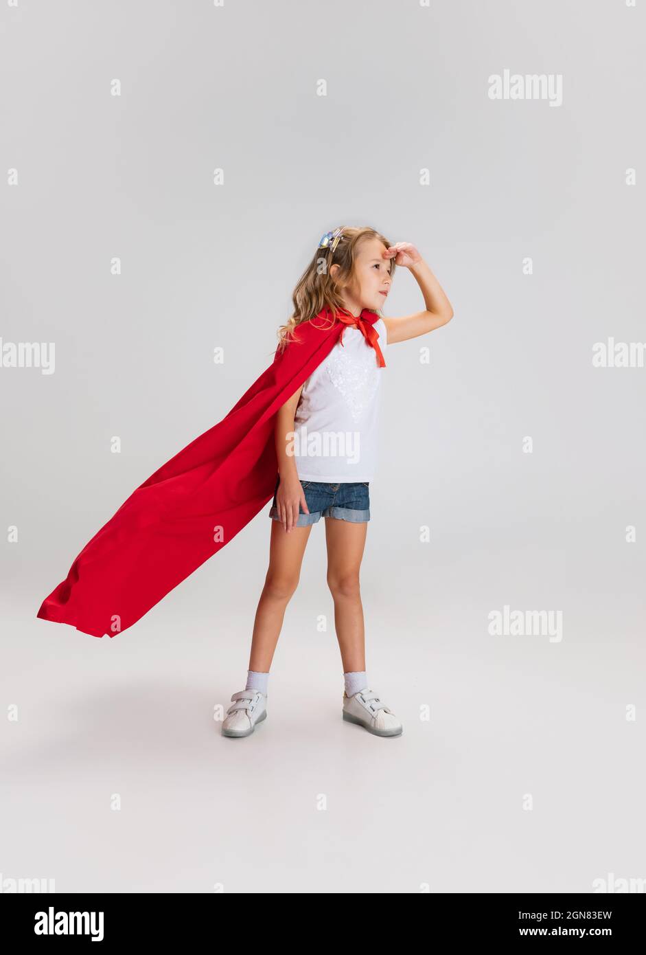 Beautiful caucasian little girl's portrait standing wearing red cape ...