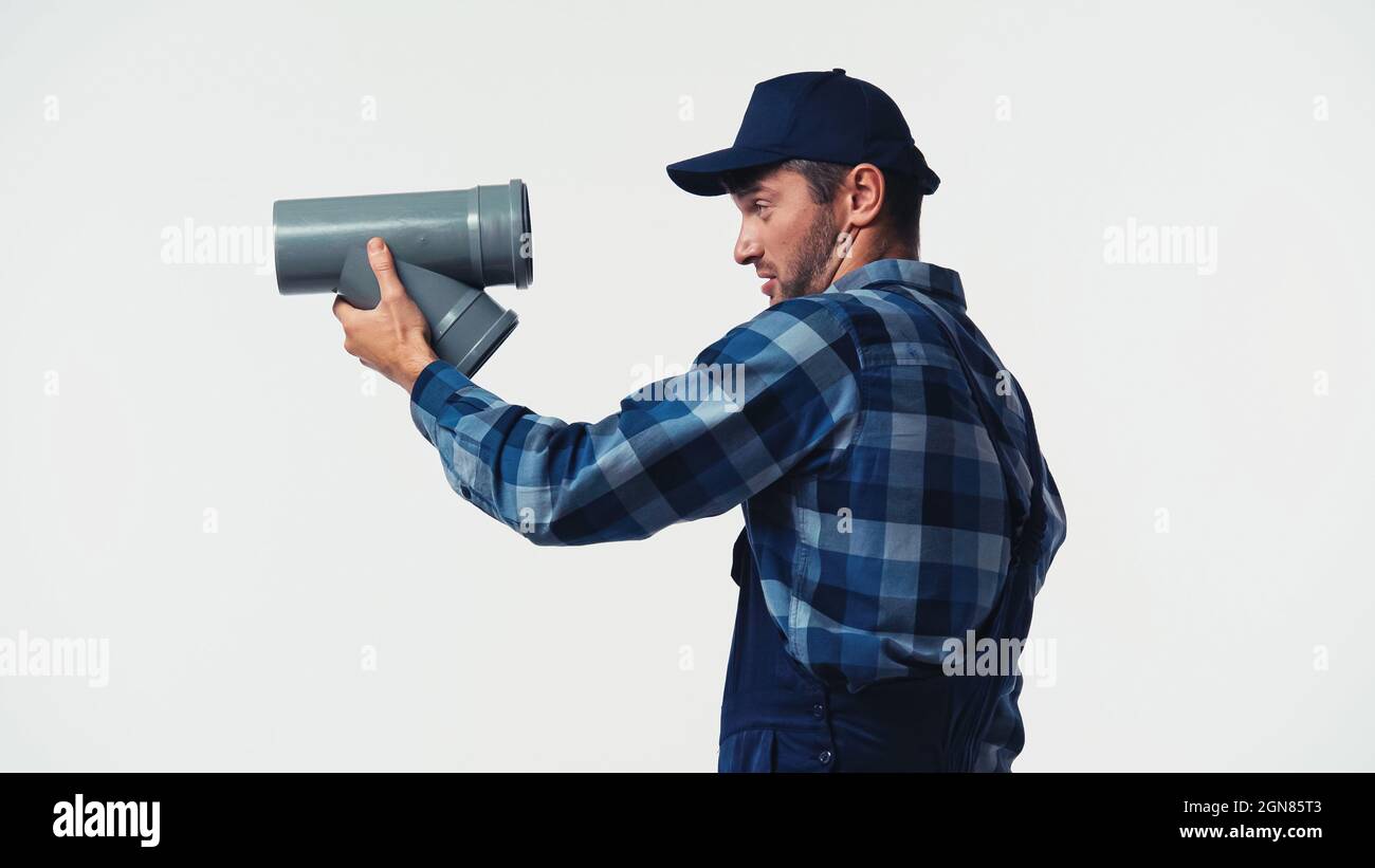 Side view of plumber looking at plastic pipe isolated on white Stock ...
