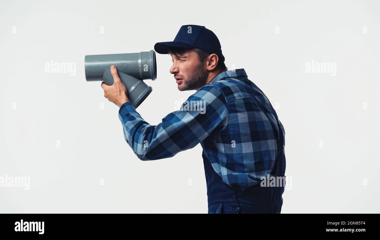 Side view of plumber looking through plastic pipe isolated on white ...