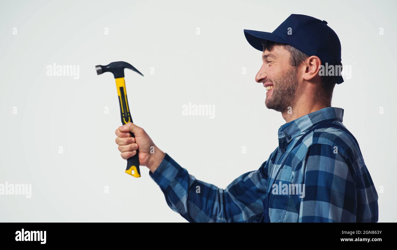 Side view of cheerful workman holding hammer isolated on white Stock ...