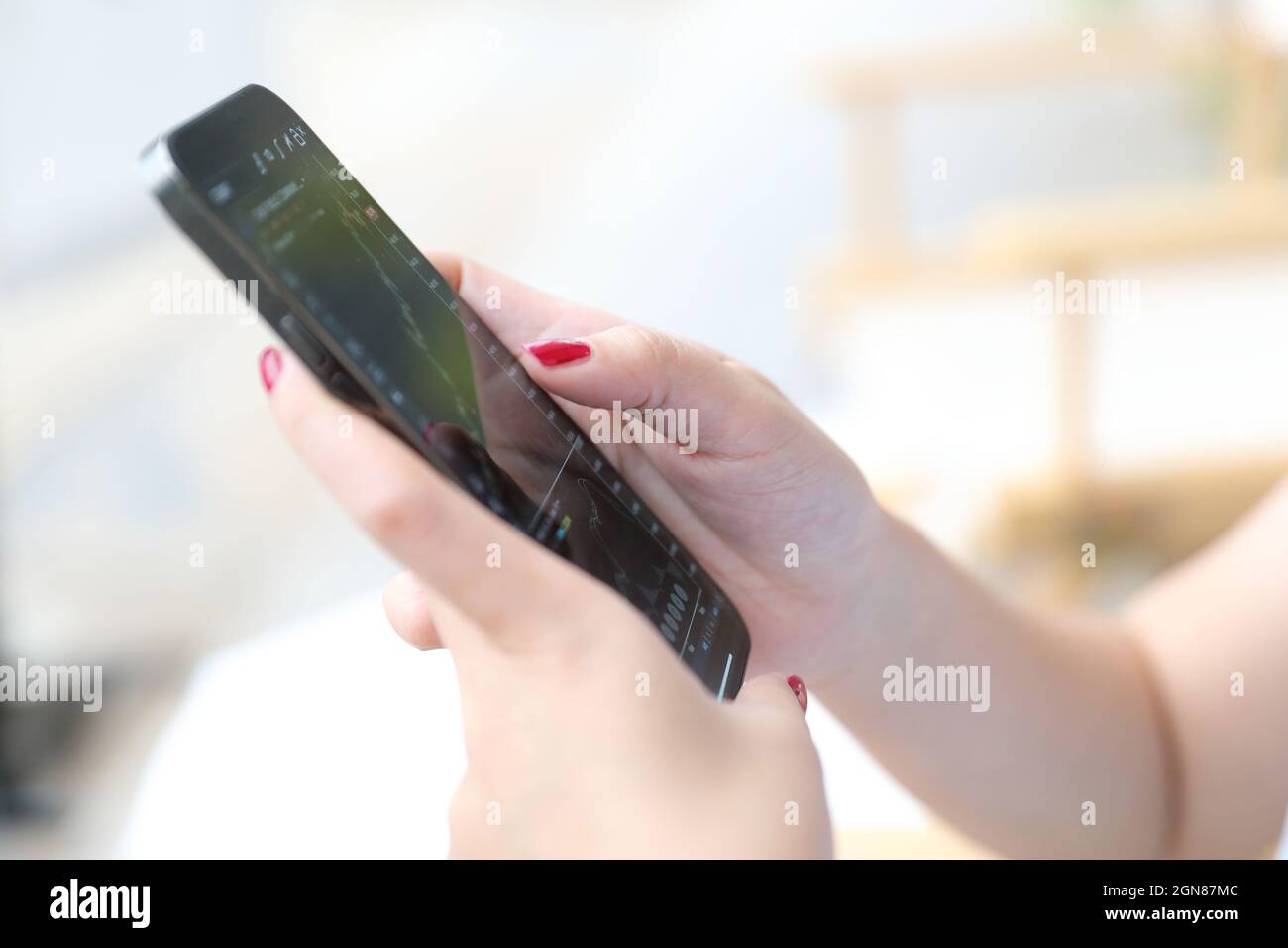 Female hand with smartphone trading stocks online in coffee shop ...