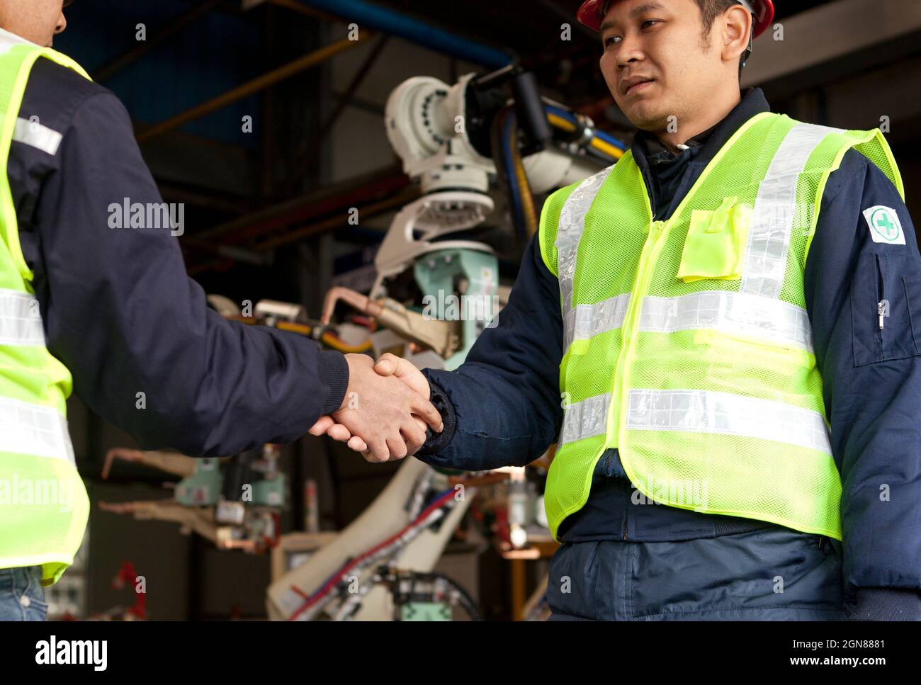 Two engineer shaking their hands at a manufacturing area Stock Photo ...