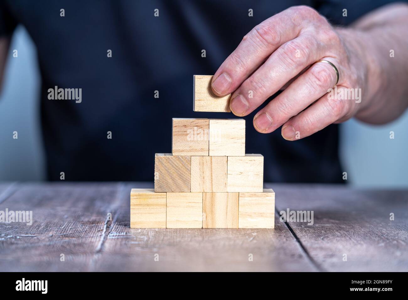 Man holding wooden block to complete a ten wooden block pyramid blank ...
