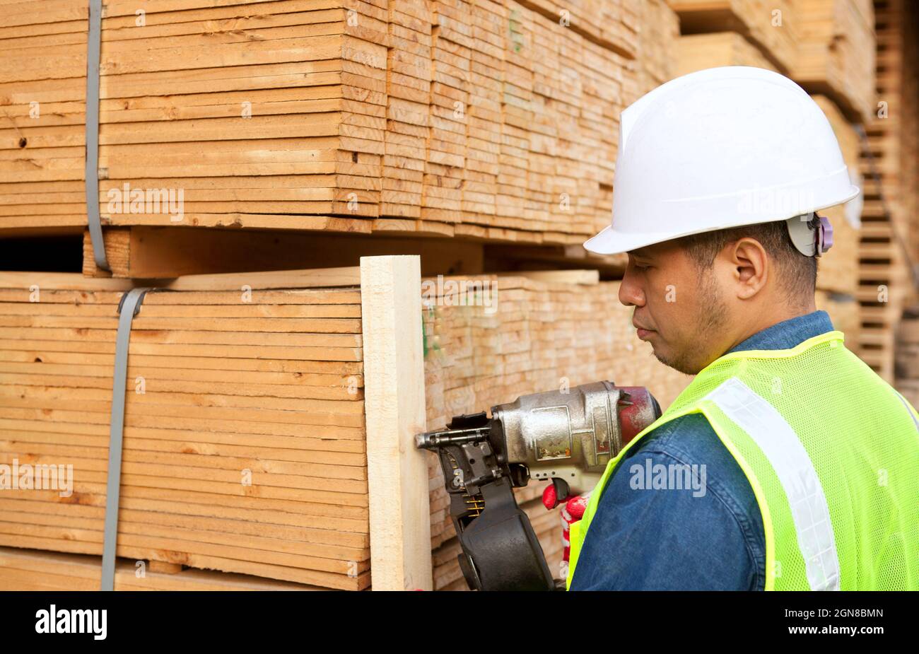 Senior worker nailing timber with nail gun Stock Photo - Alamy