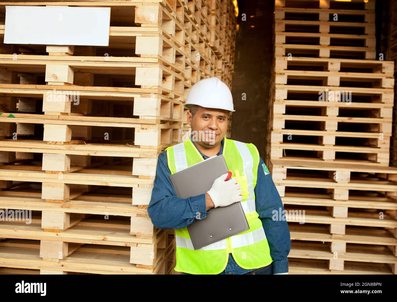 Senior worker standing relaxed in warehouse pallet Stock Photo - Alamy