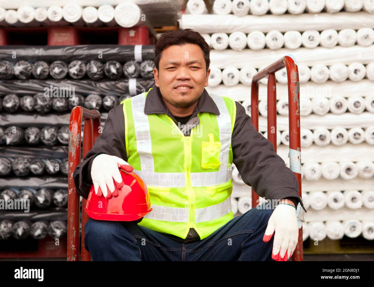 Textile factory worker sitting beside raw material fabrics stacked ...