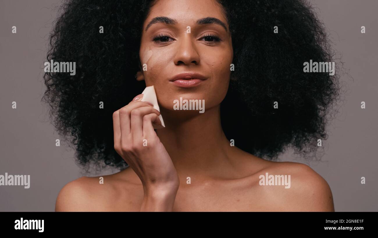 african american woman applying makeup foundation with sponge isolated ...