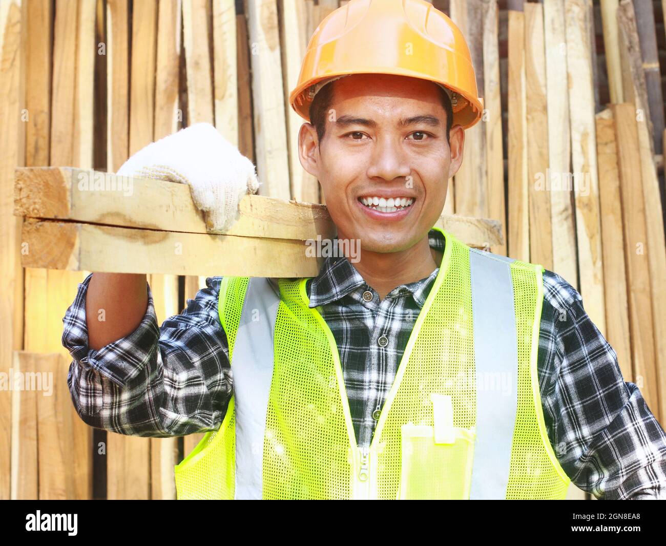 Man worker carpenter with helmet and safety vest carrying wood smiling ...