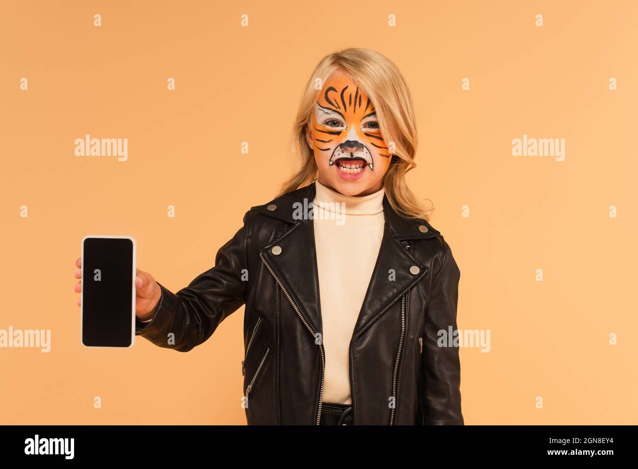child with tiger face painting showing smartphone with blank screen and ...