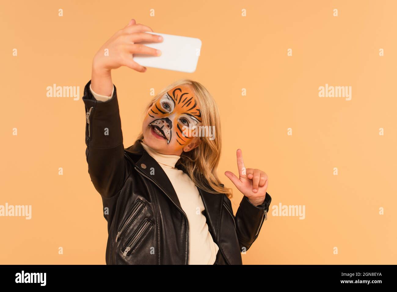 child with tiger face painting pointing up with finger while taking ...