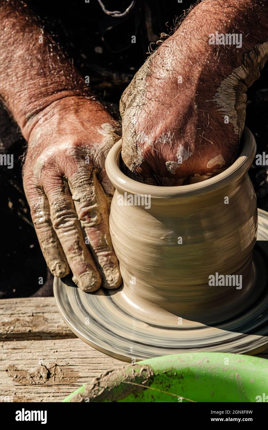 Hands of a potter shaping a clay pot on a potter wheel Stock Photo - Alamy