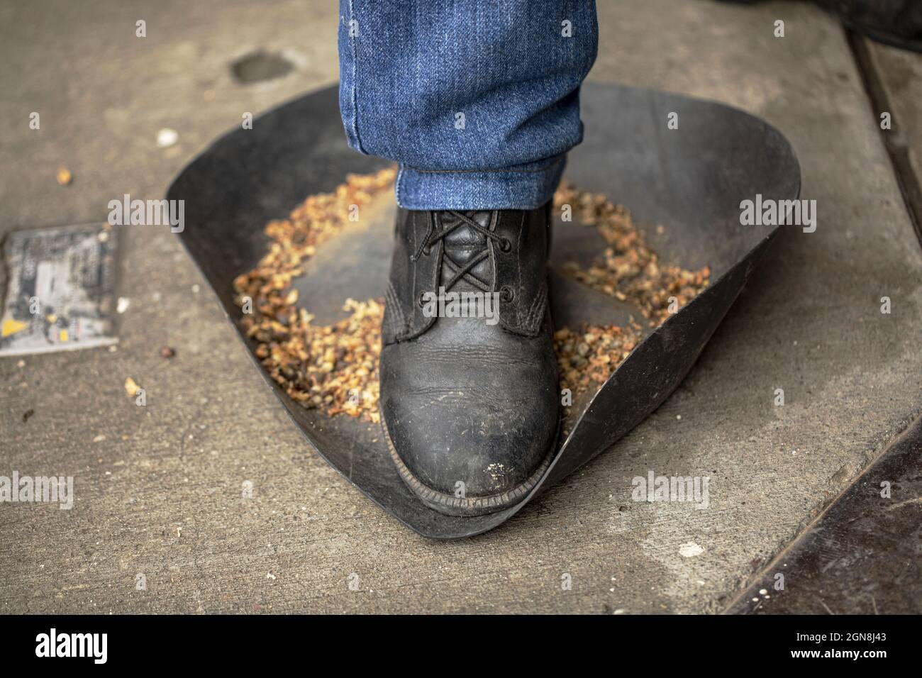 High angle shot of a male"s foot squashing some nuts in a black bowl ...