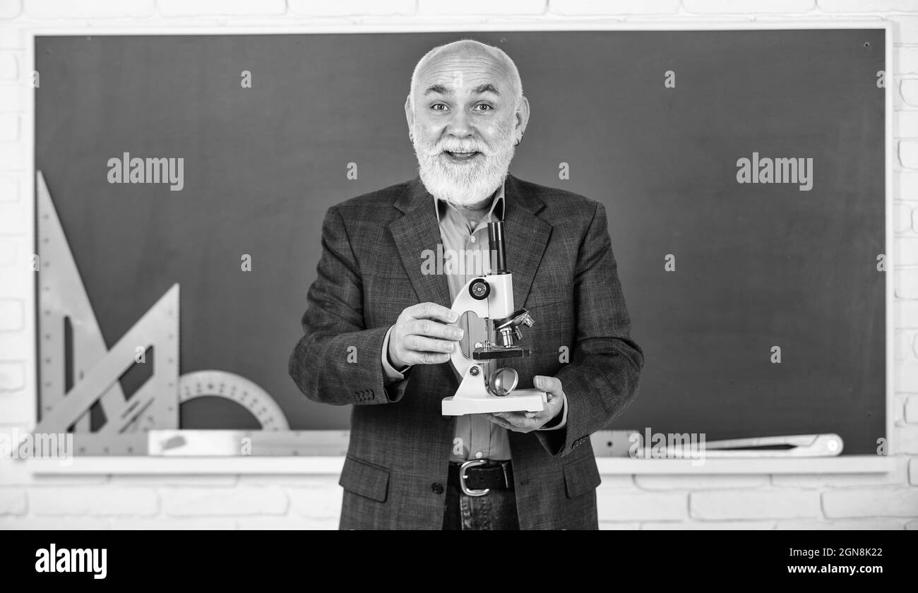happy senior teacher use microscope. chemistry in school laboratory ...