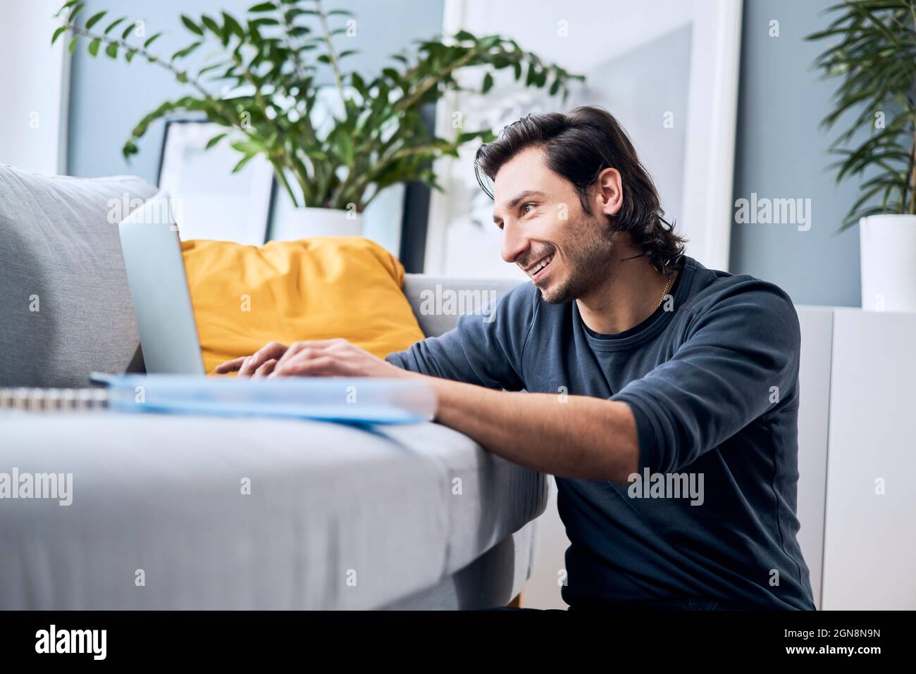 Smiling male student using laptop while learning at home Stock Photo ...