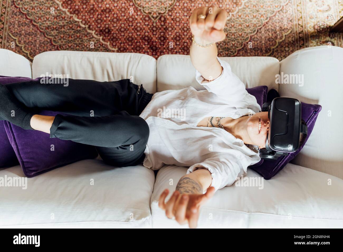 Woman gesturing while enjoying virtual reality simulator on sofa at ...