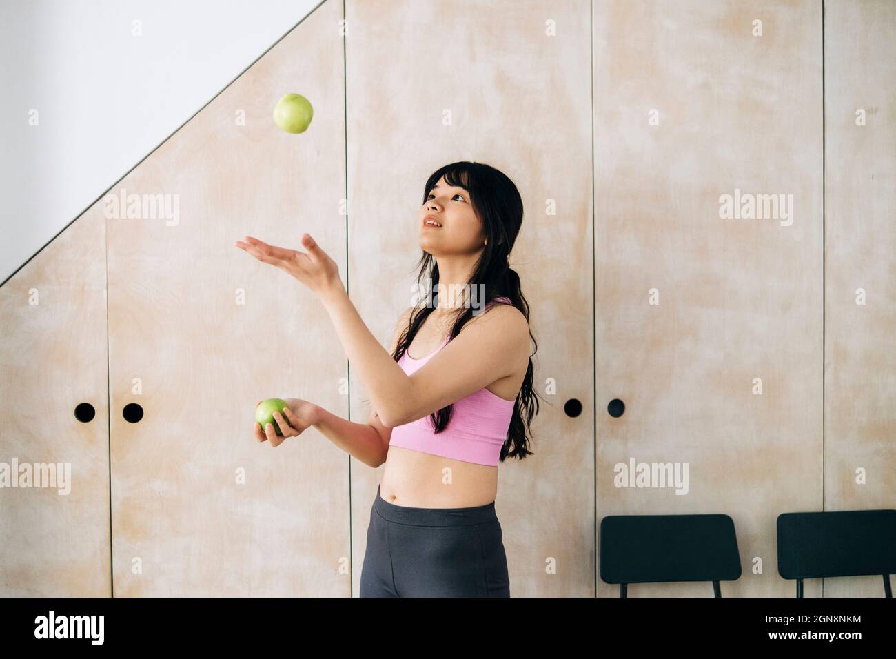 Woman juggling apples while standing in front of cabinet at home Stock ...