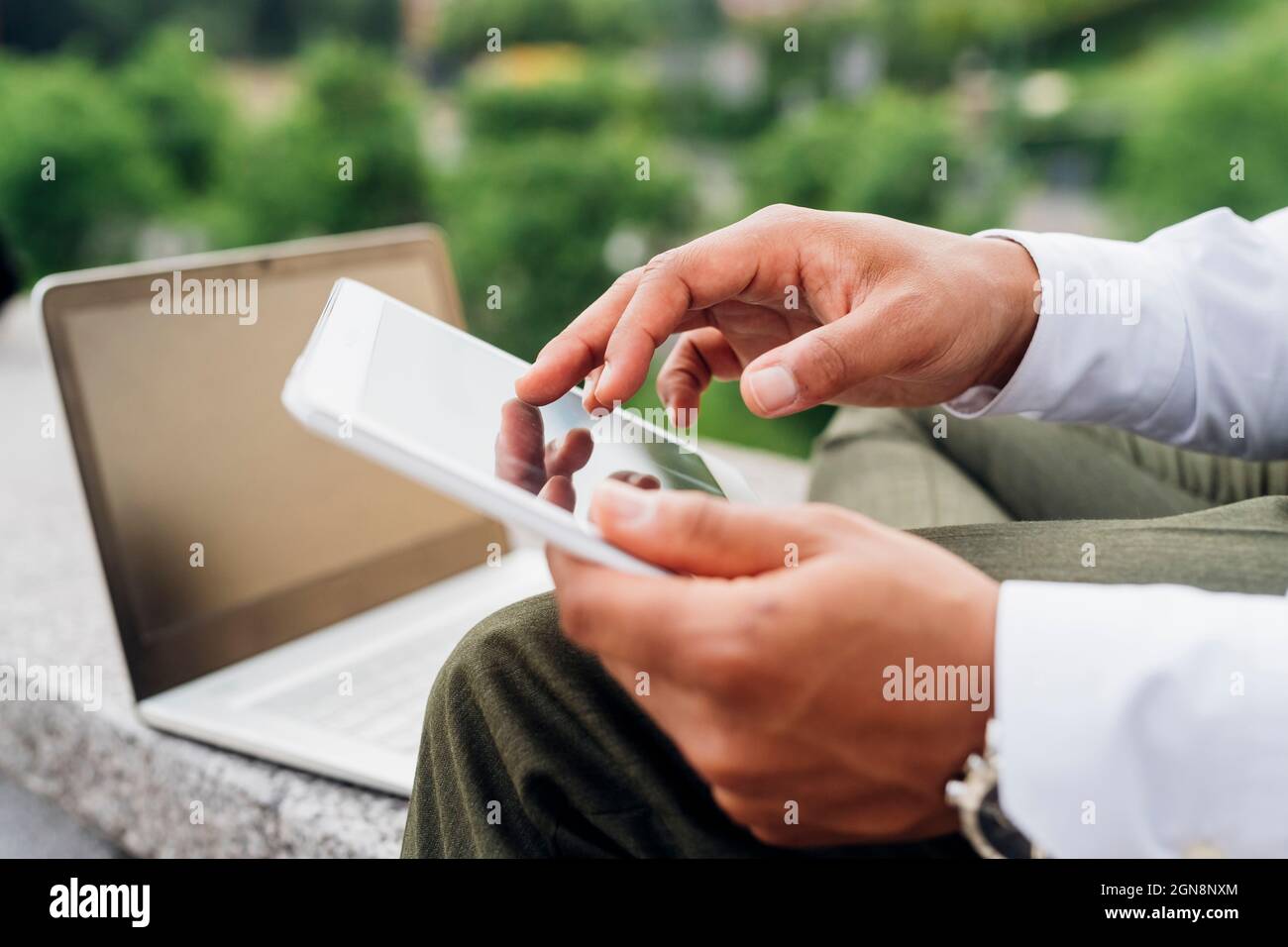 Male professional with laptop using digital tablet while sitting on ...