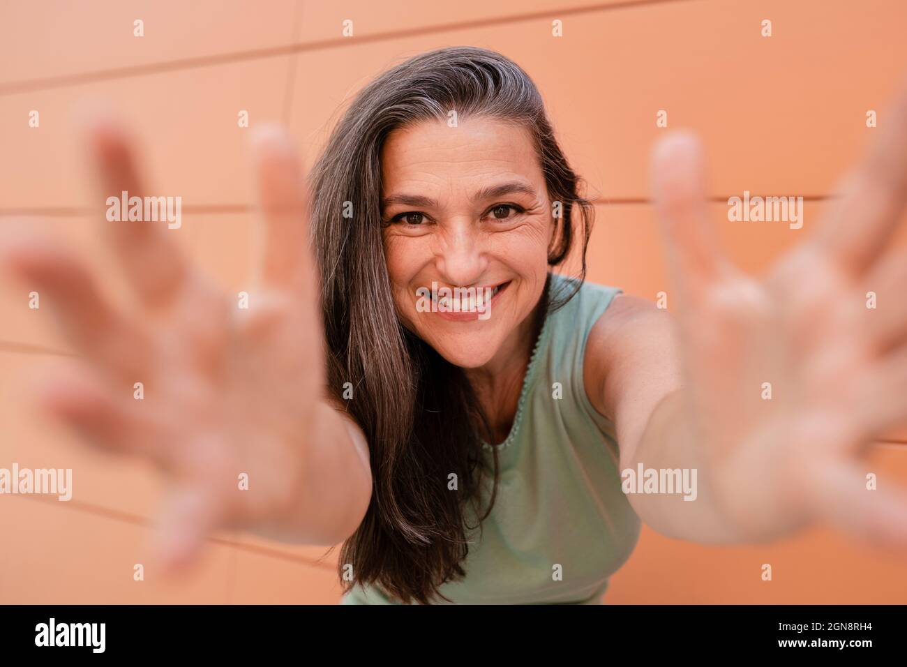 Smiling beautiful mature woman reaching with arms outstretched Stock ...