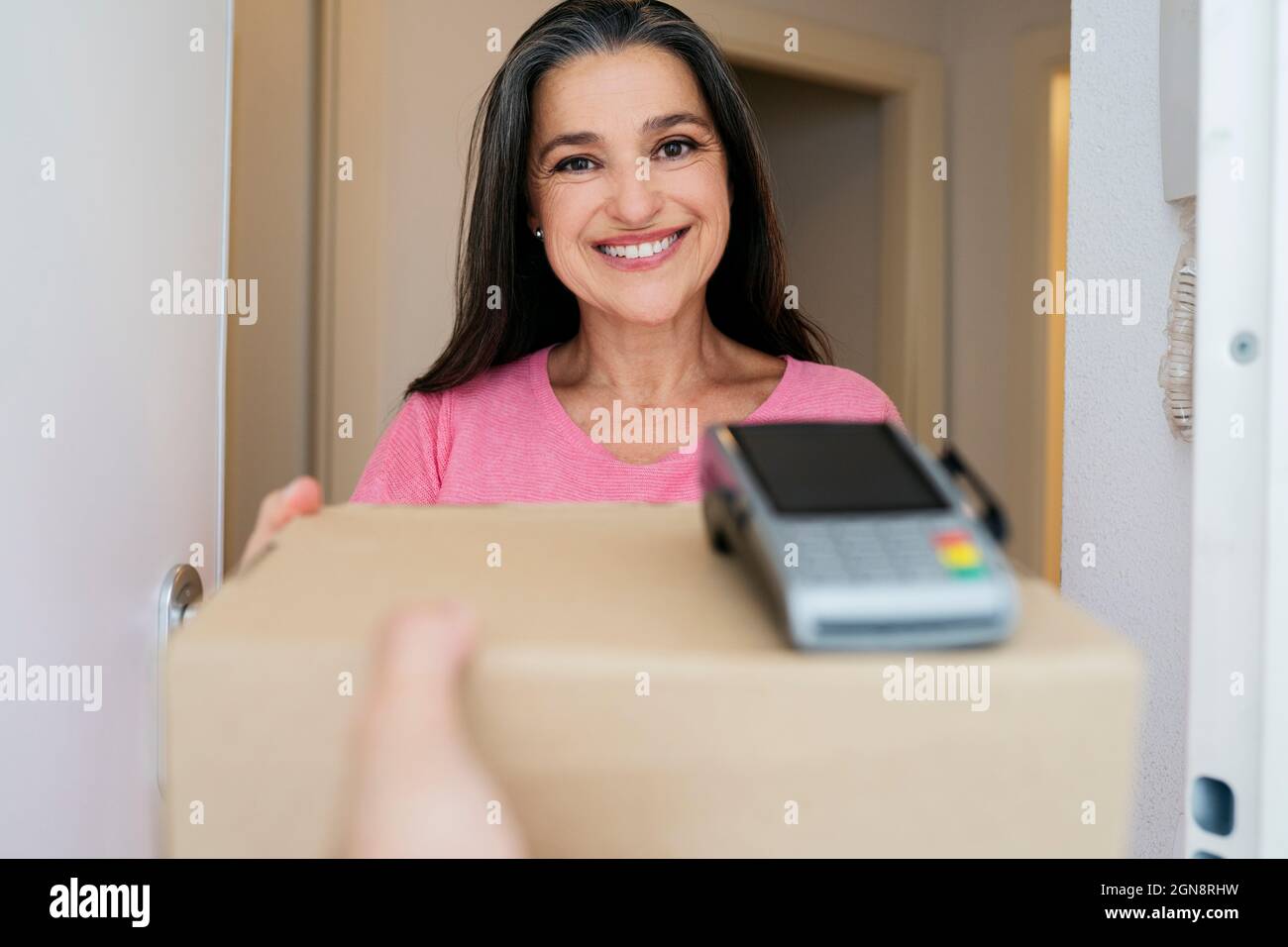 Smiling woman receiving package from delivery person Stock Photo - Alamy