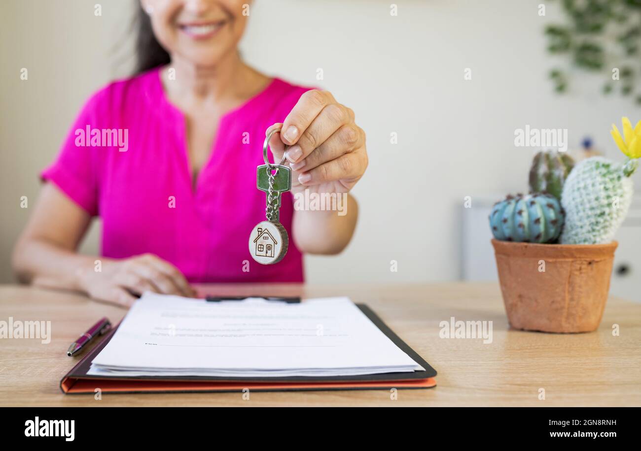 Smiling female real estate agent giving house key at home office Stock ...