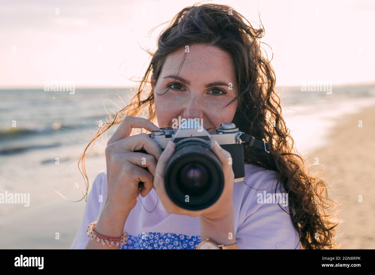Young woman holding camera at beach Stock Photo - Alamy