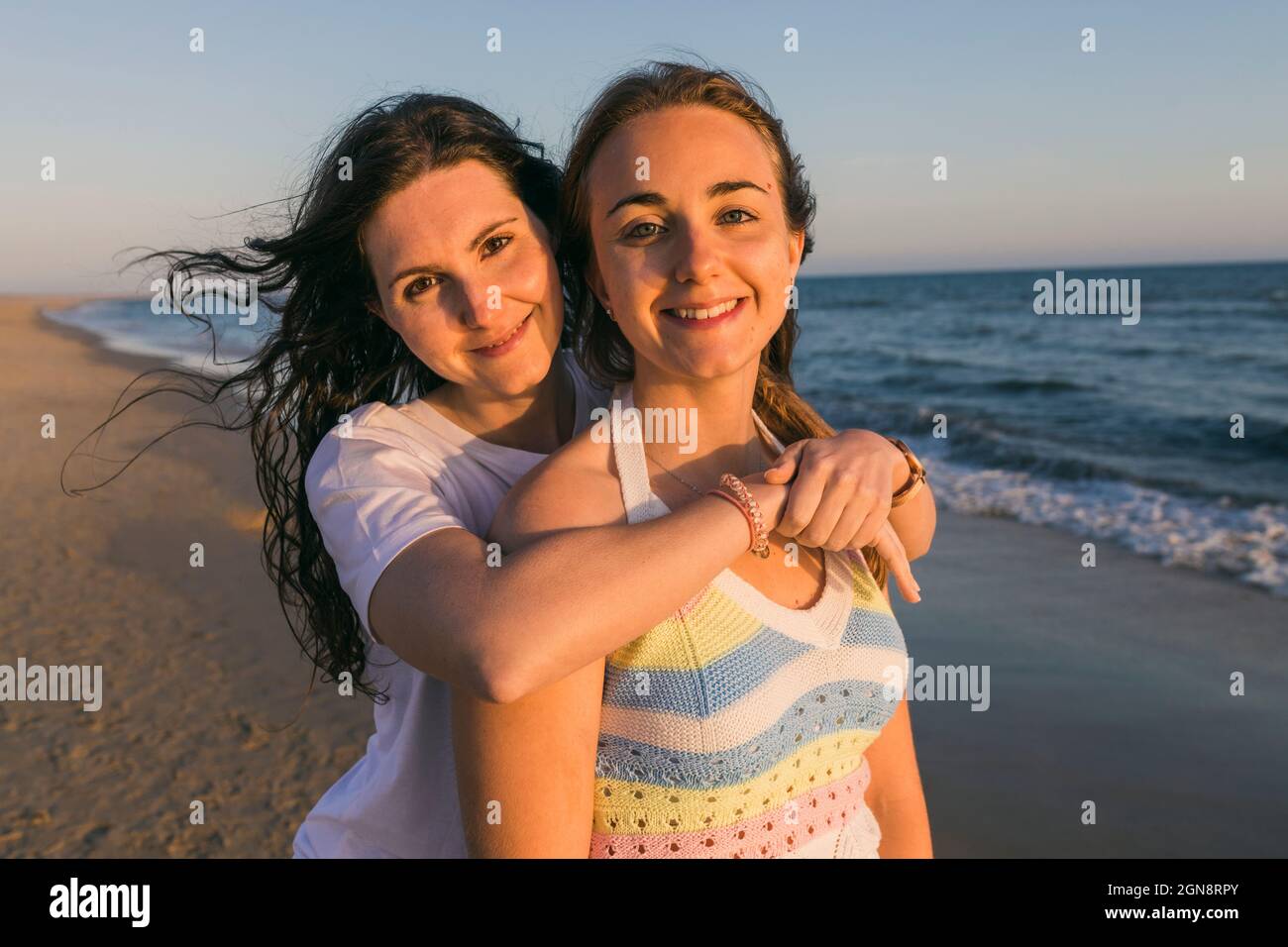 Woman embracing female friend at beach Stock Photo - Alamy