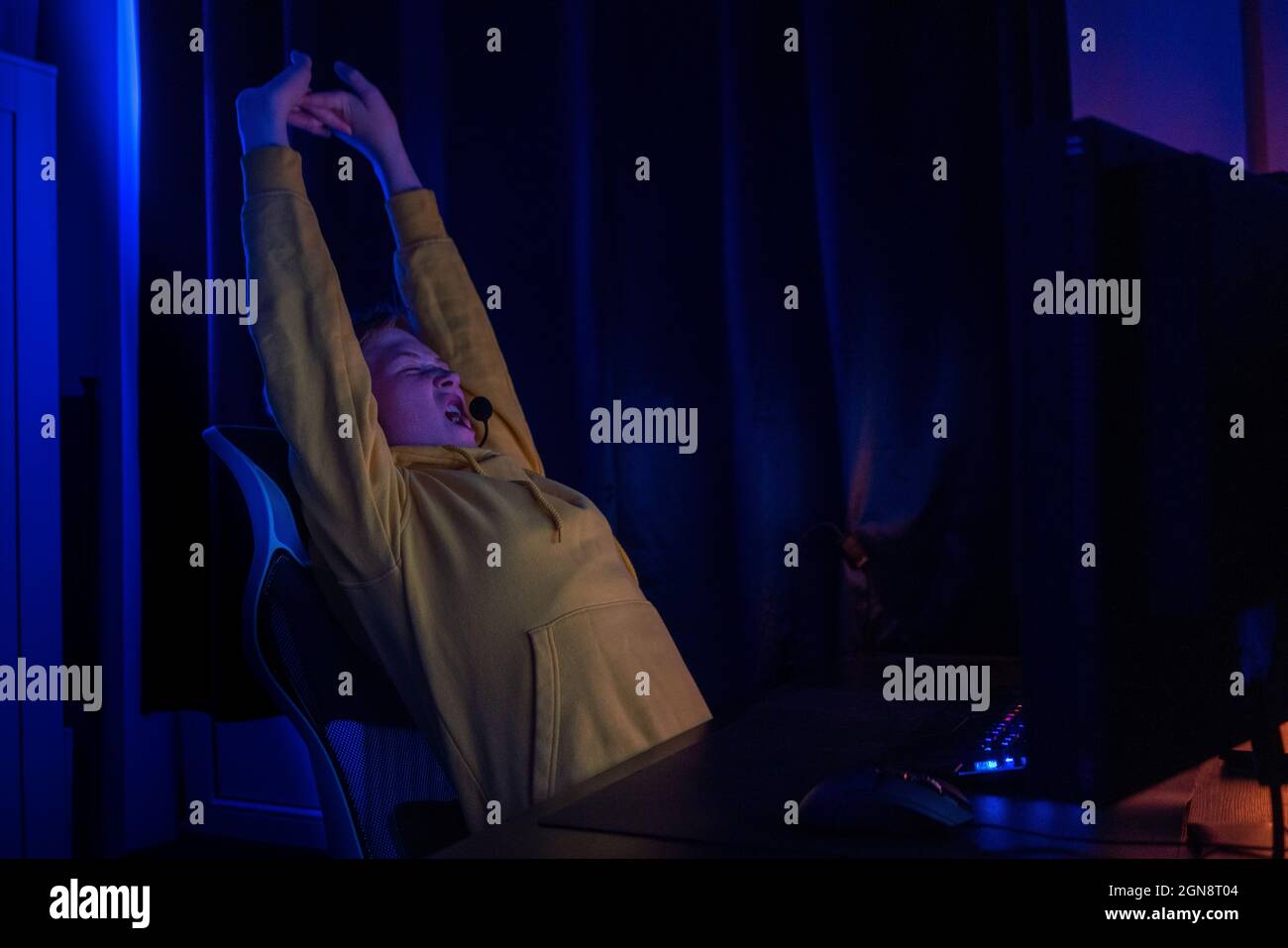 Tired boy stretching while playing video game at home Stock Photo - Alamy