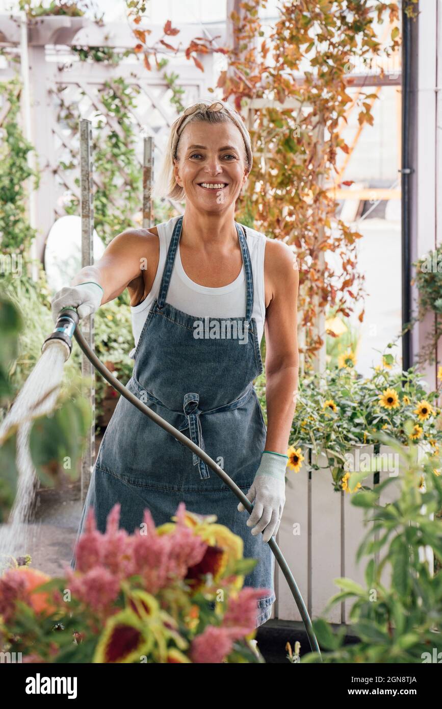 Female greenhouse worker watering plants at nursery Stock Photo - Alamy