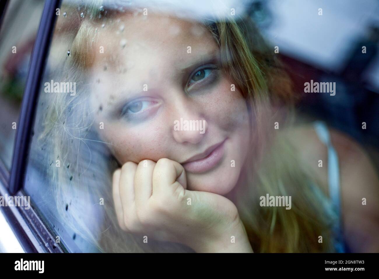 Girl day dreaming while looking through car window Stock Photo - Alamy