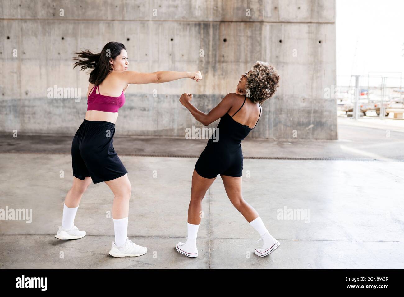 Female punching friend while practicing boxing sports Stock Photo - Alamy