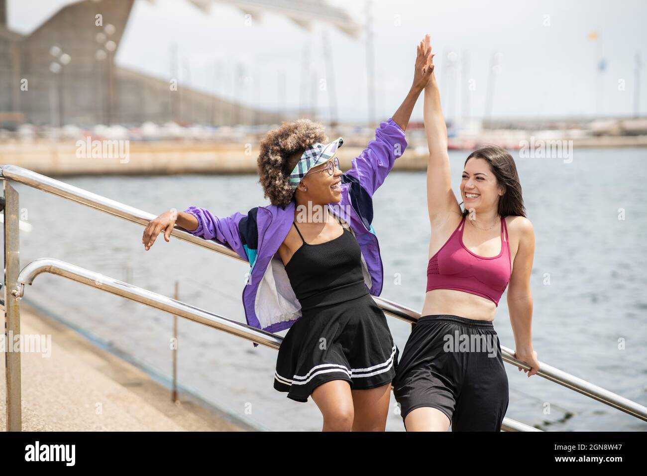 Happy female friends giving high-five to each other during sunny day ...