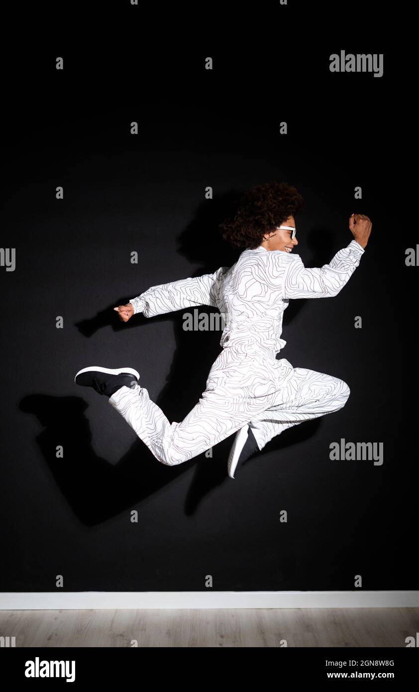 Excited female fashion model jumping in studio Stock Photo - Alamy