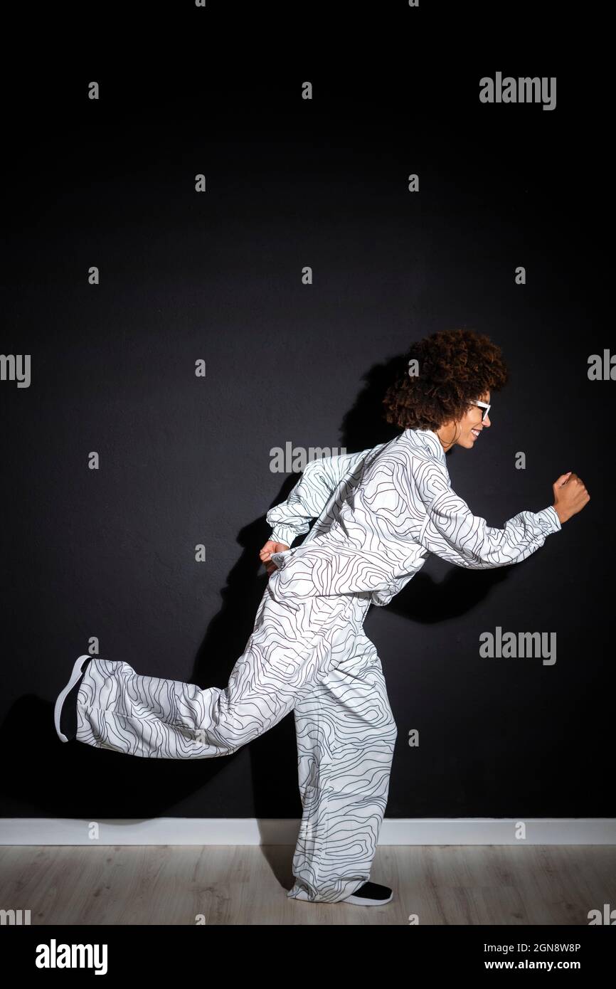 Woman running by black wall in studio Stock Photo - Alamy