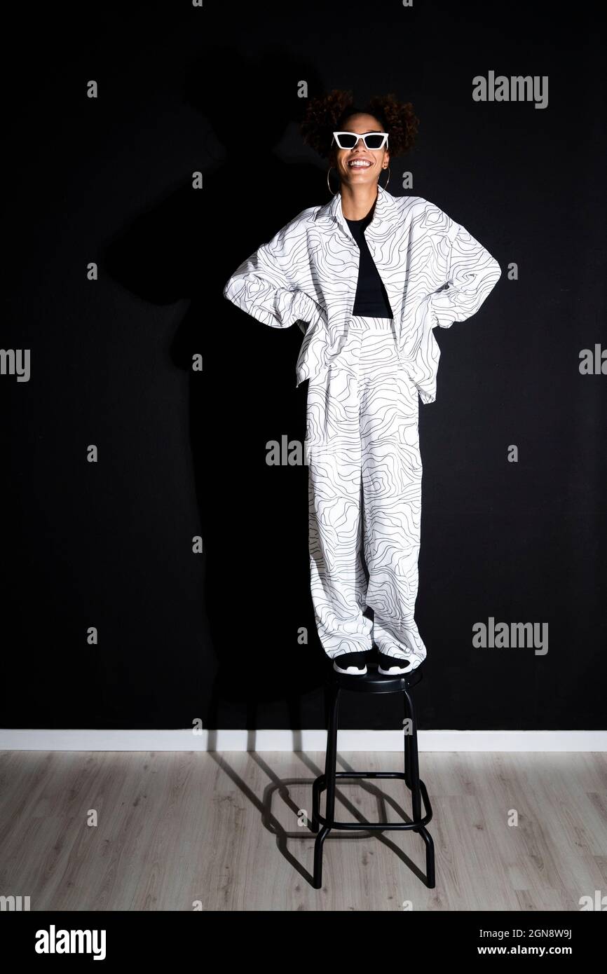 Female fashion model standing on stool in front of black wall Stock ...