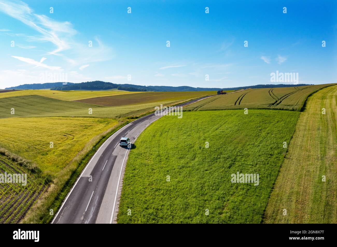 Drone view of lone car driving country road stretching between ...