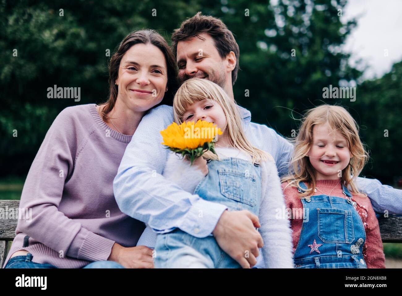 Family sitting on a bench and smiling Stock Photo - Alamy