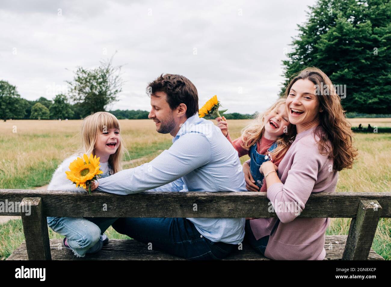 Smiling parents sitting with daughters on bench Stock Photo - Alamy