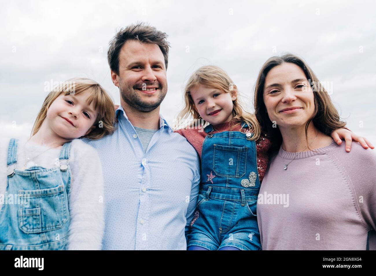 Smiling parents and daughters standing together Stock Photo - Alamy