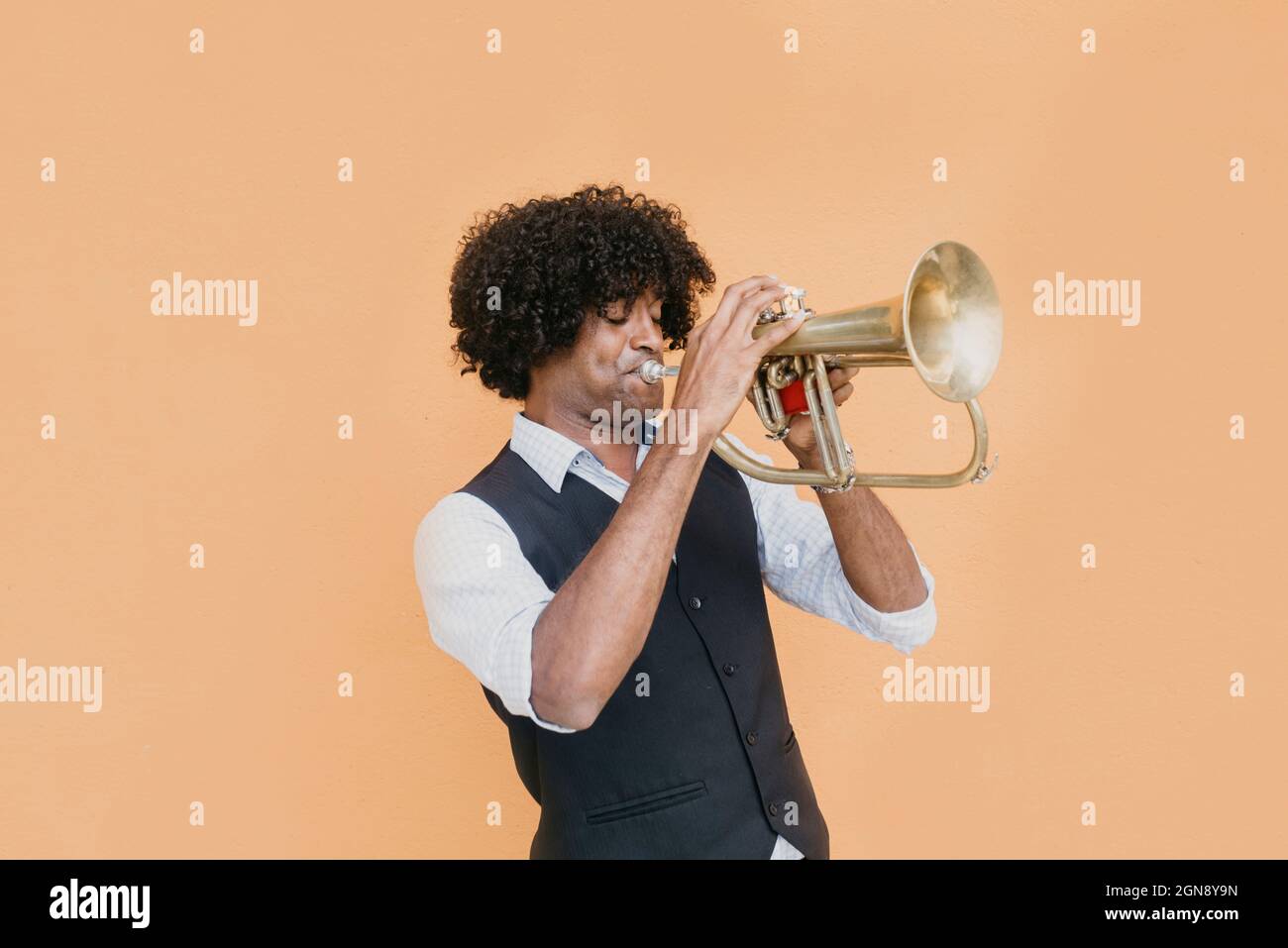 Man with eyes closed playing trumpet in front of beige wall Stock Photo ...