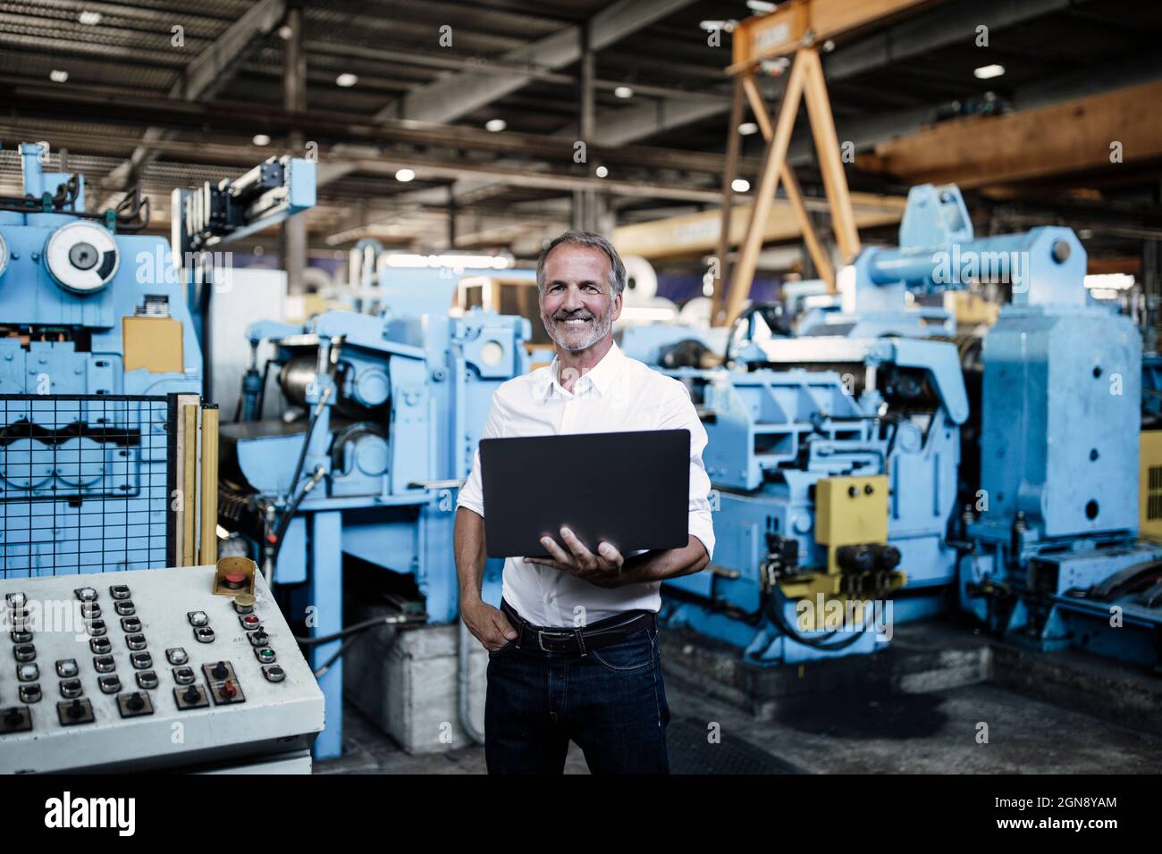 Smiling male professional holding laptop at steel mil Stock Photo - Alamy