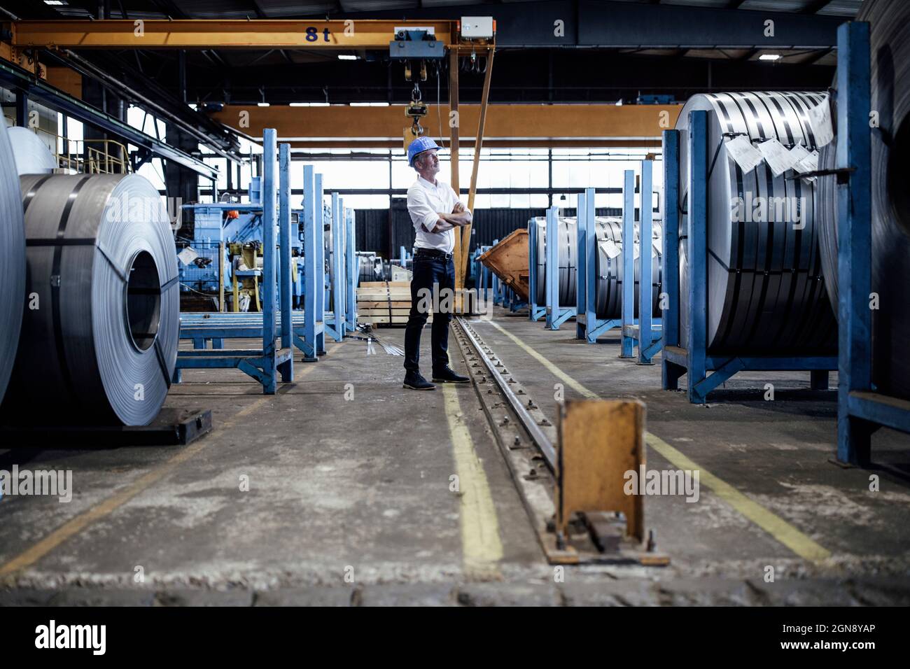 Male engineer standing with arms crossed in steel warehouse Stock Photo ...