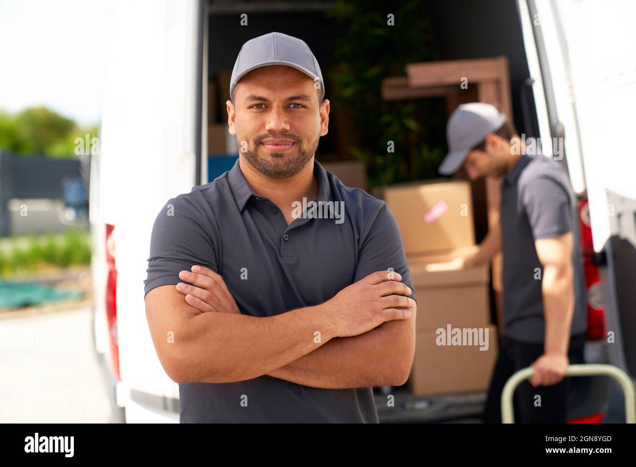 Male delivery person wearing cap standing with arms crossed Stock Photo ...