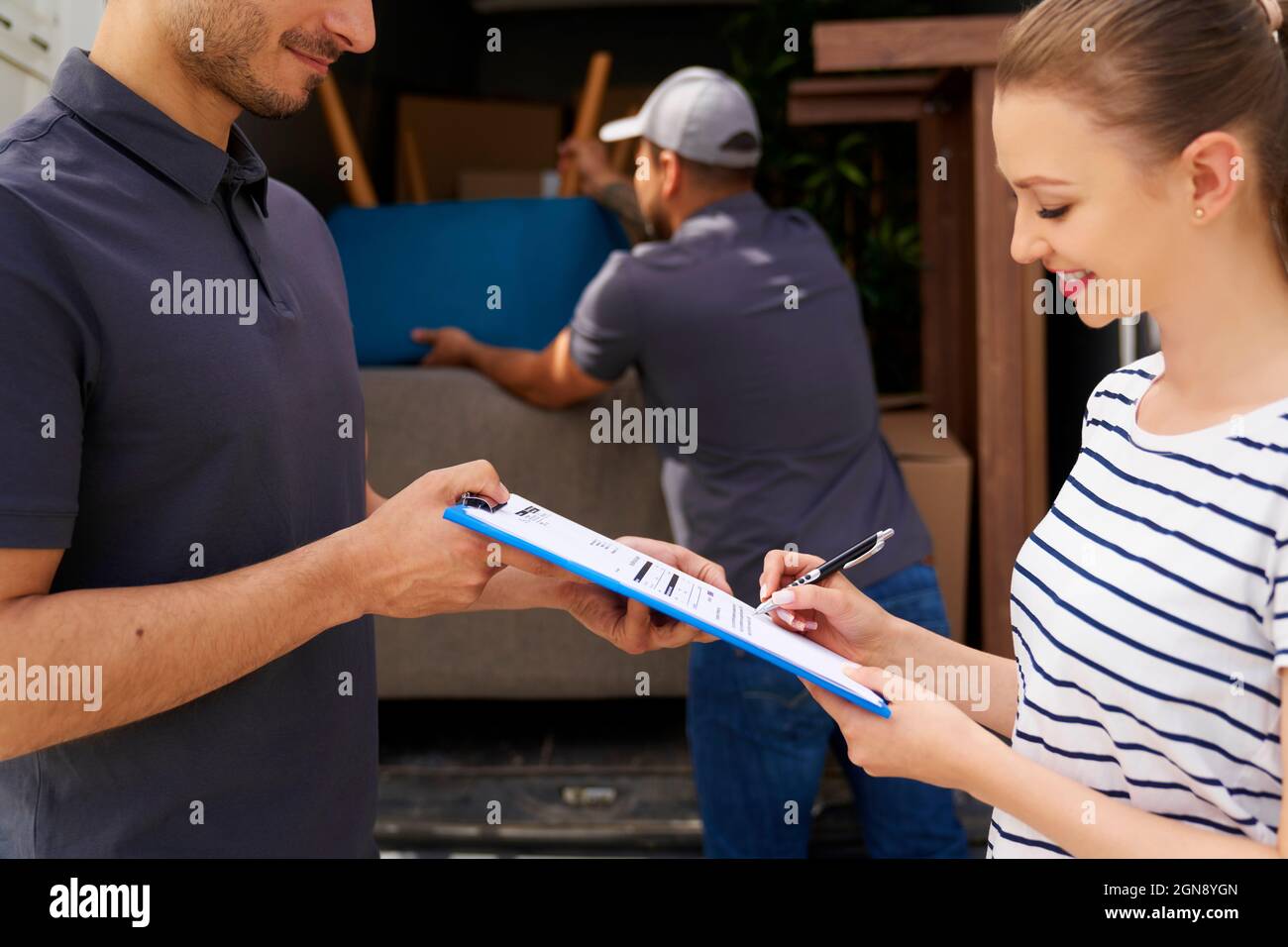 Female customer signing documents on clipboard Stock Photo - Alamy