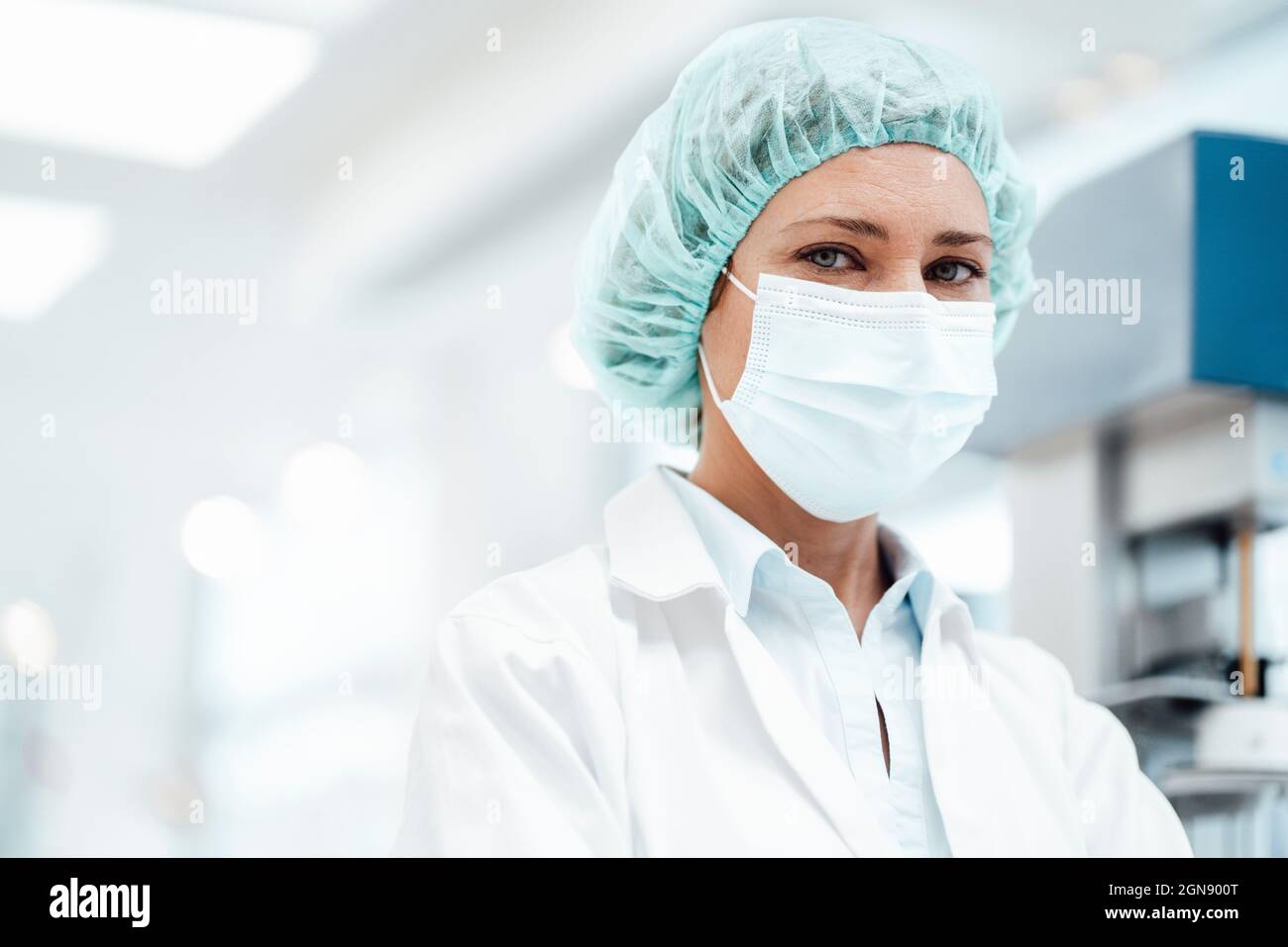 Female pharmacist with surgical cap and protective face mask at ...