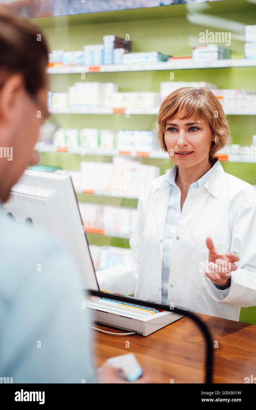 Female pharmacist talking to customer at pharmacy Stock Photo - Alamy