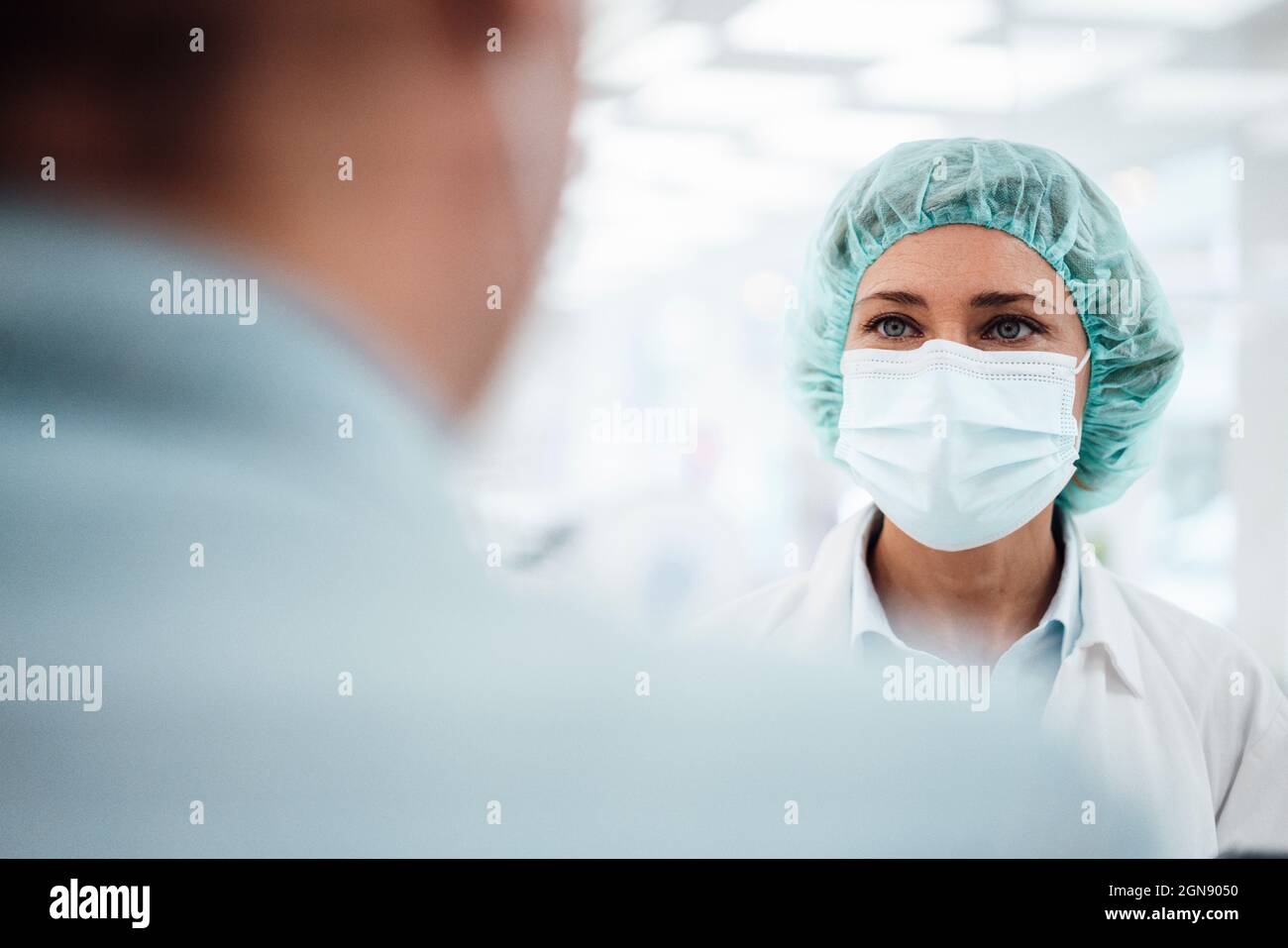 Female pharmacist wearing protective face mask discussing with male ...