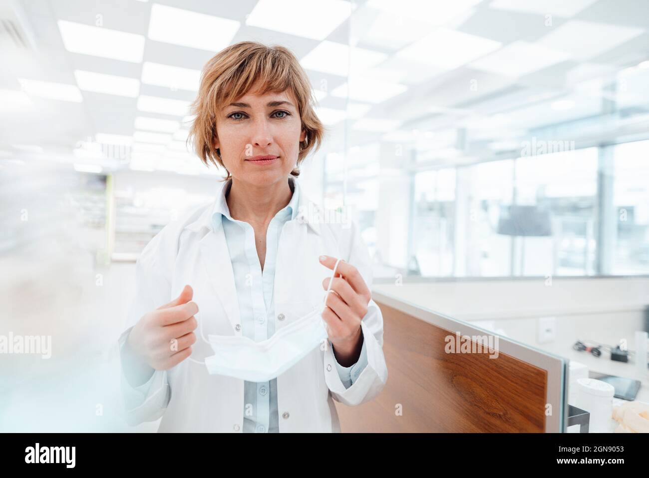 Female pharmacist holding protective face mask at pharmacy store Stock ...