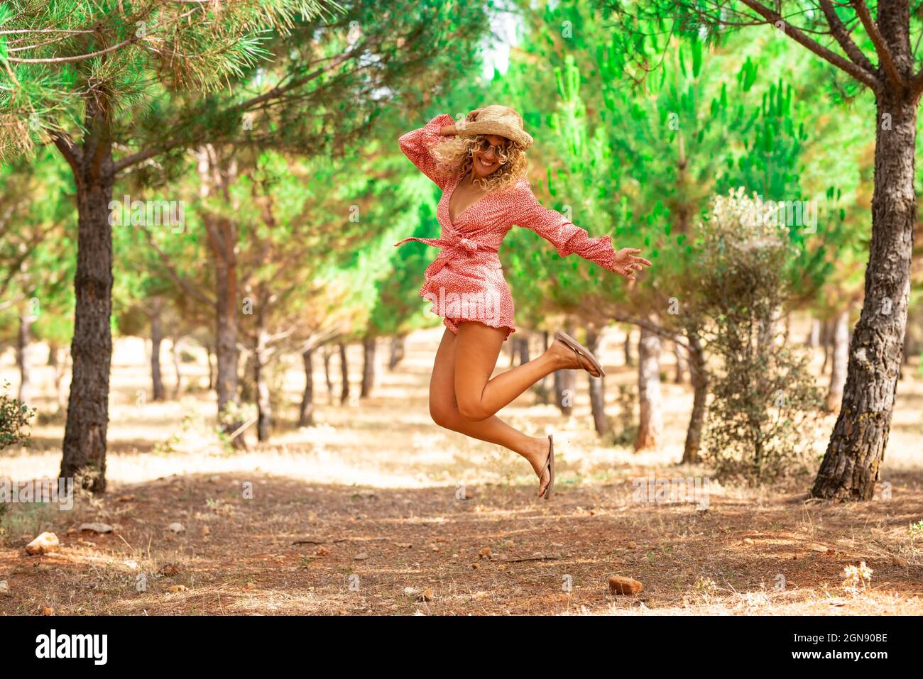 Excited woman jumping amidst trees at park Stock Photo - Alamy