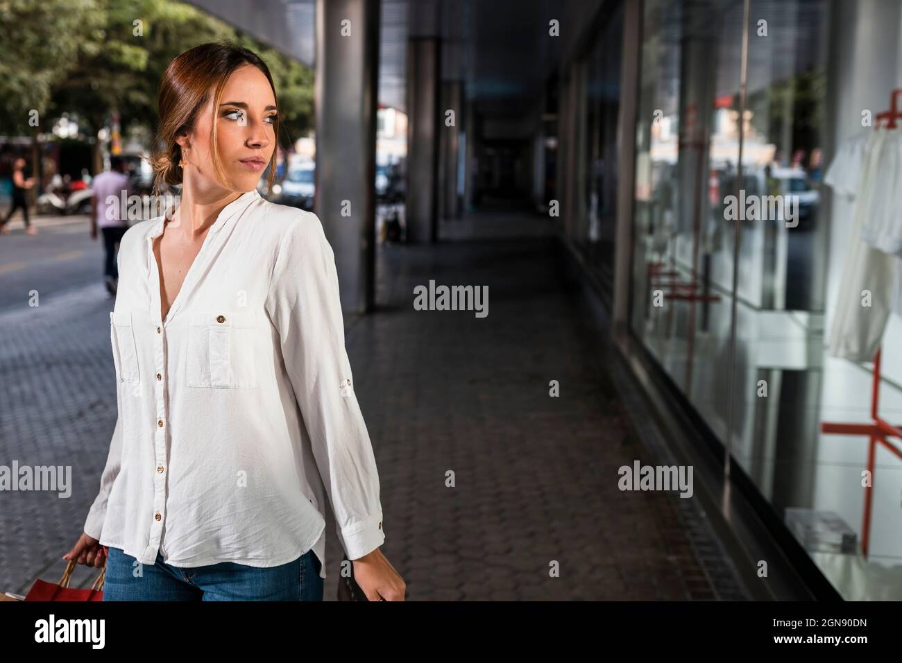 Young woman looking at store window while shopping Stock Photo - Alamy